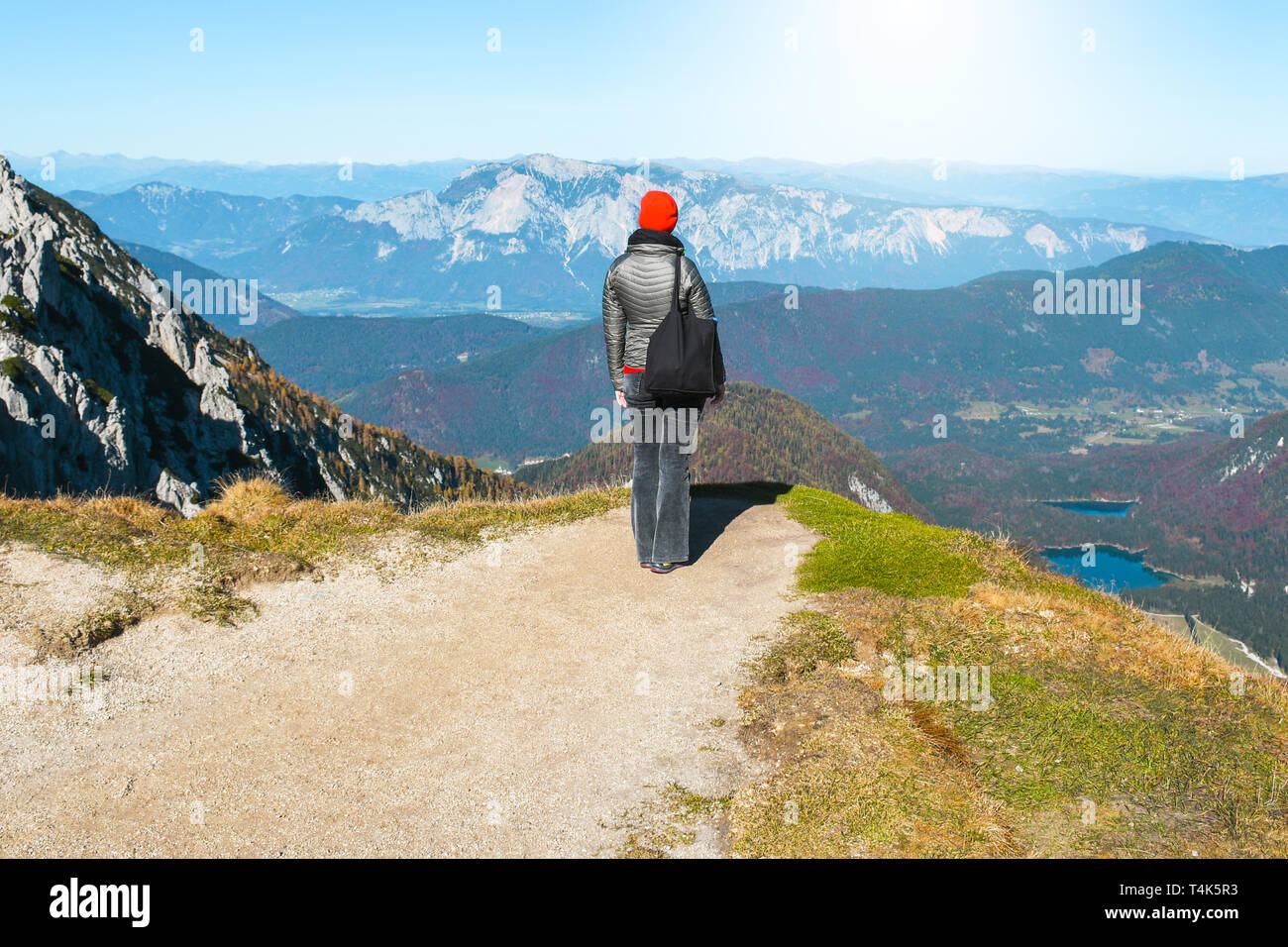 Girl with orange hat and black bag standing on an edge of a cliff on a ...