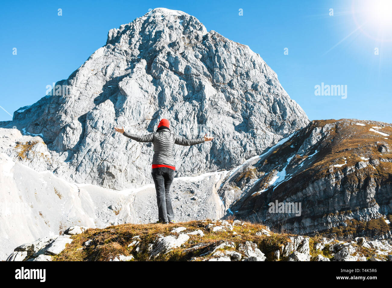 Excited girl exercising with orange hat looking to a mountain peak on a ...