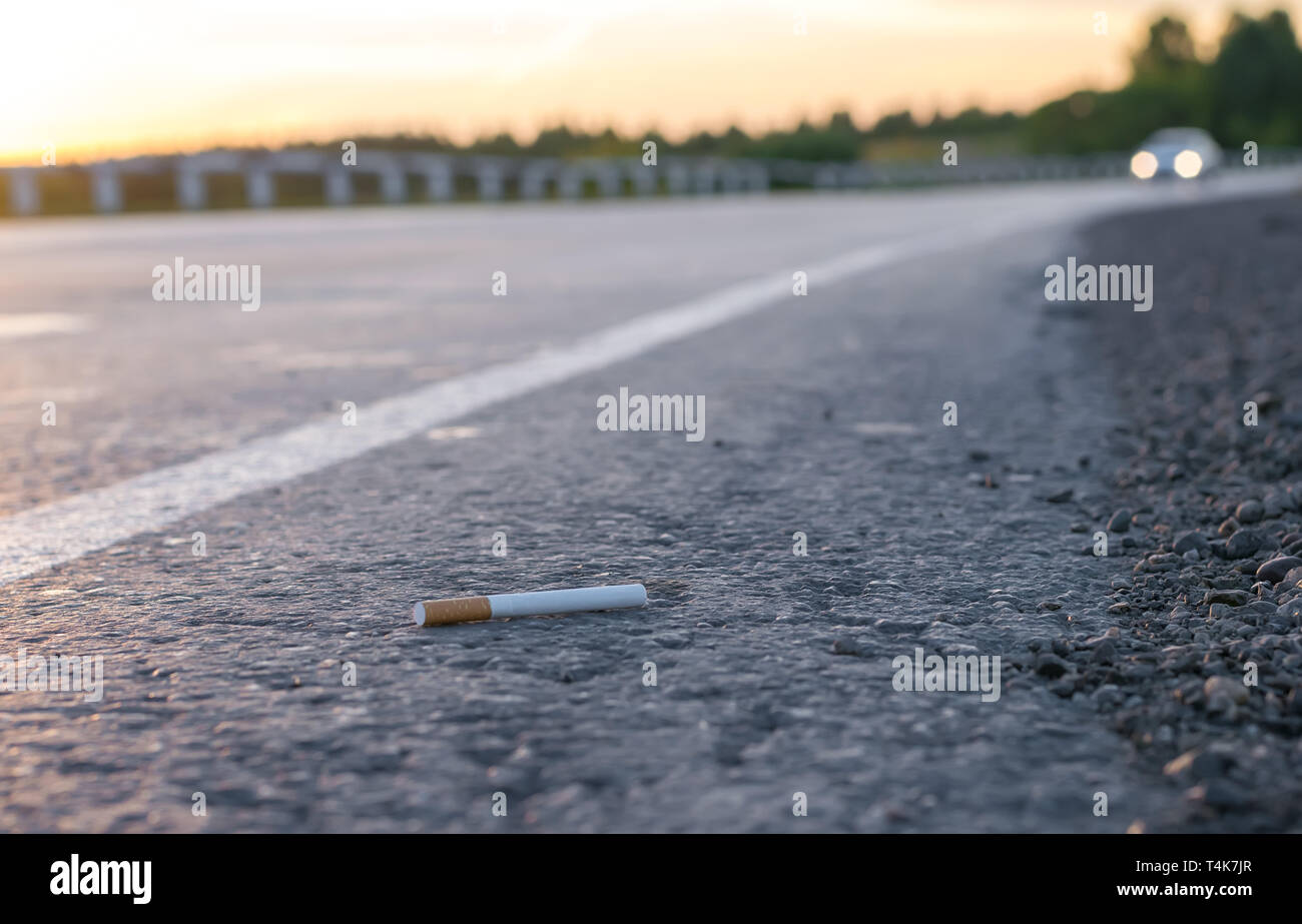 view of cigarette lying on the asphalt on a country road on the ...