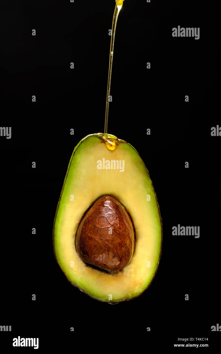 Avocado oil concept. Oil pouring on avocado. Oil drop on fruit. Black ...