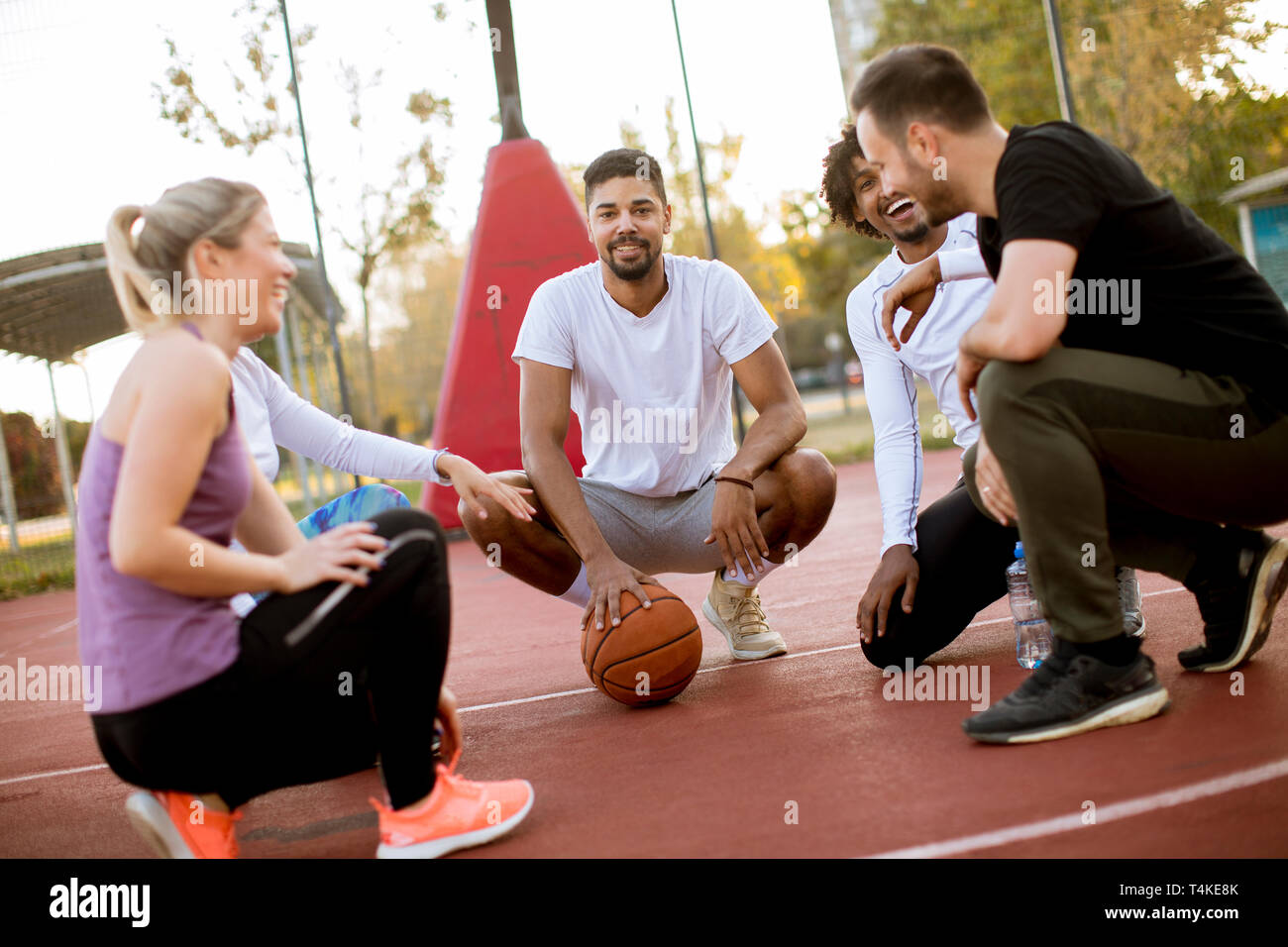 Multiethnic group of young basketball players resting on court together ...