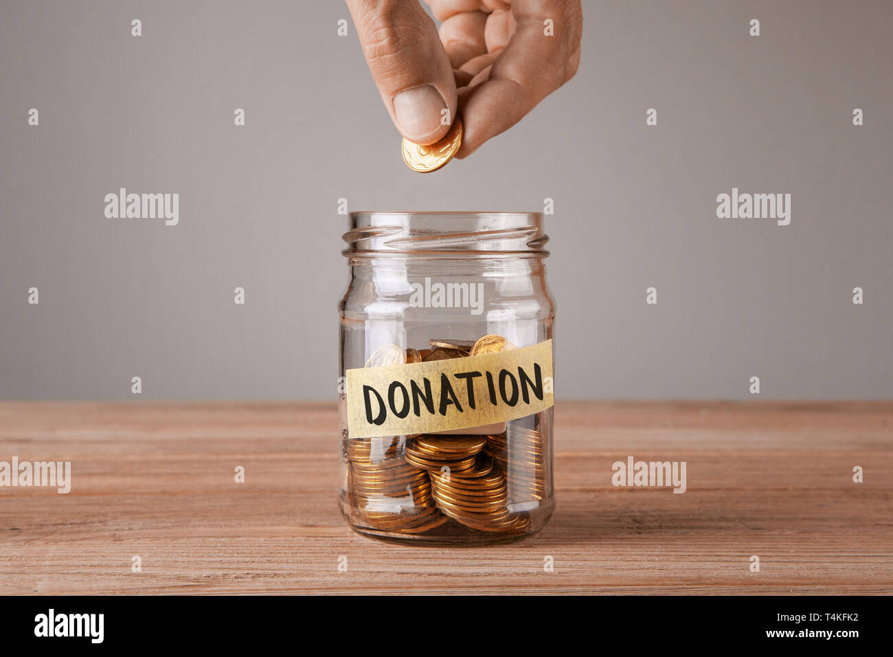 Donation. Glass jar with coins and an inscription donation. Man holds ...