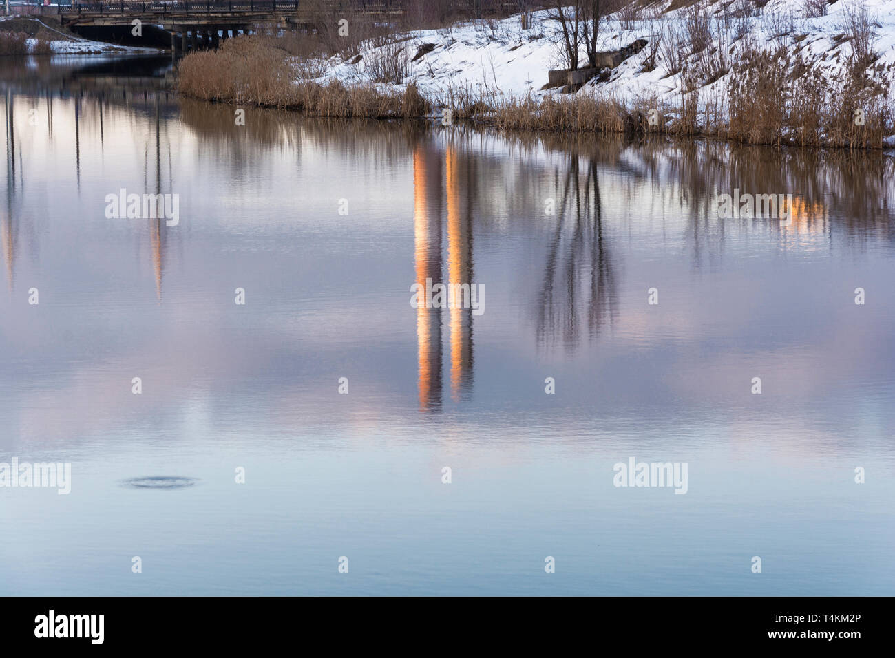 Beautiful reflection of trees and tall pipes in the blue mirror surface ...