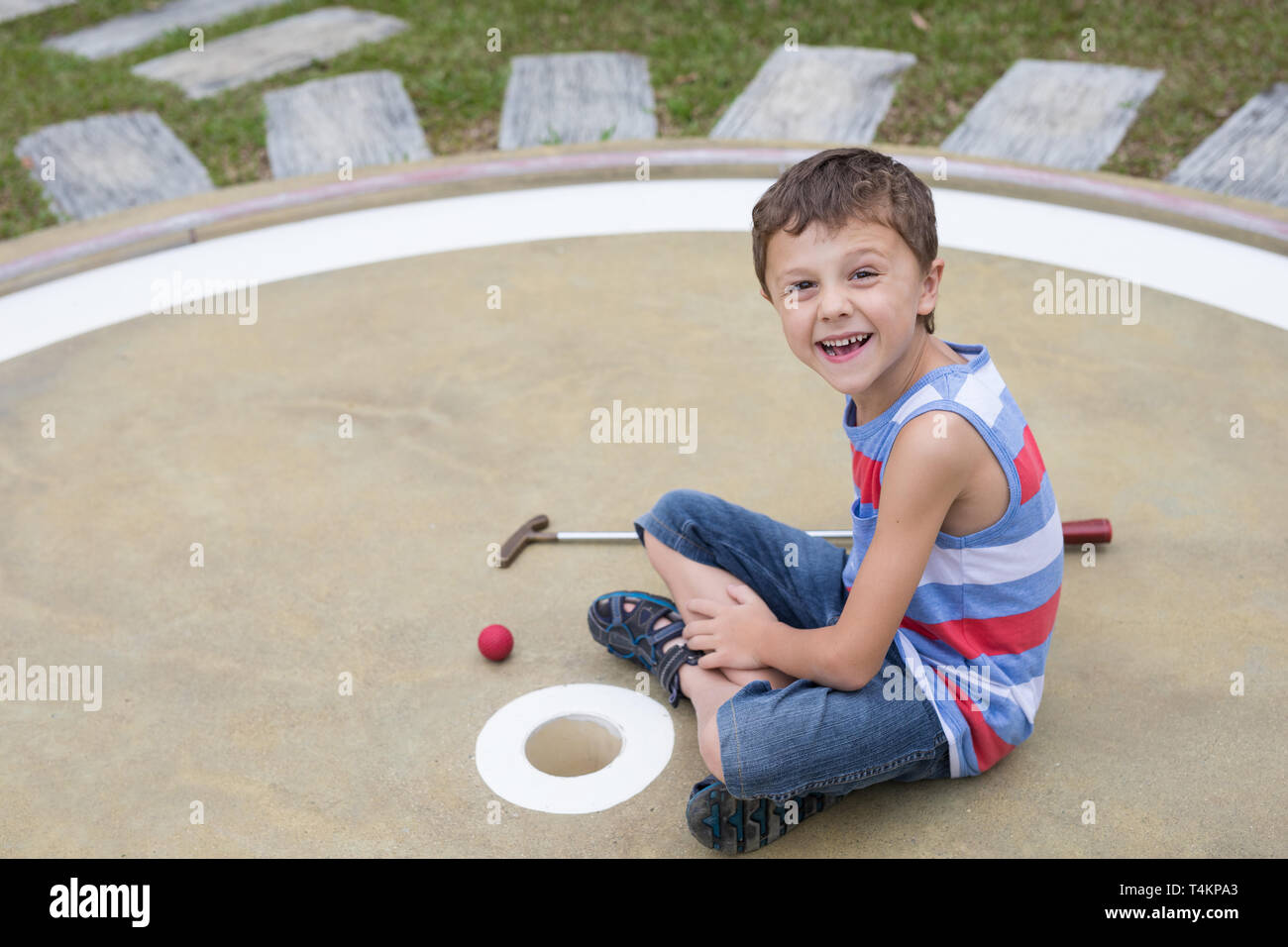 Happy little boy playing mini golf playing mini golf in a park at the ...