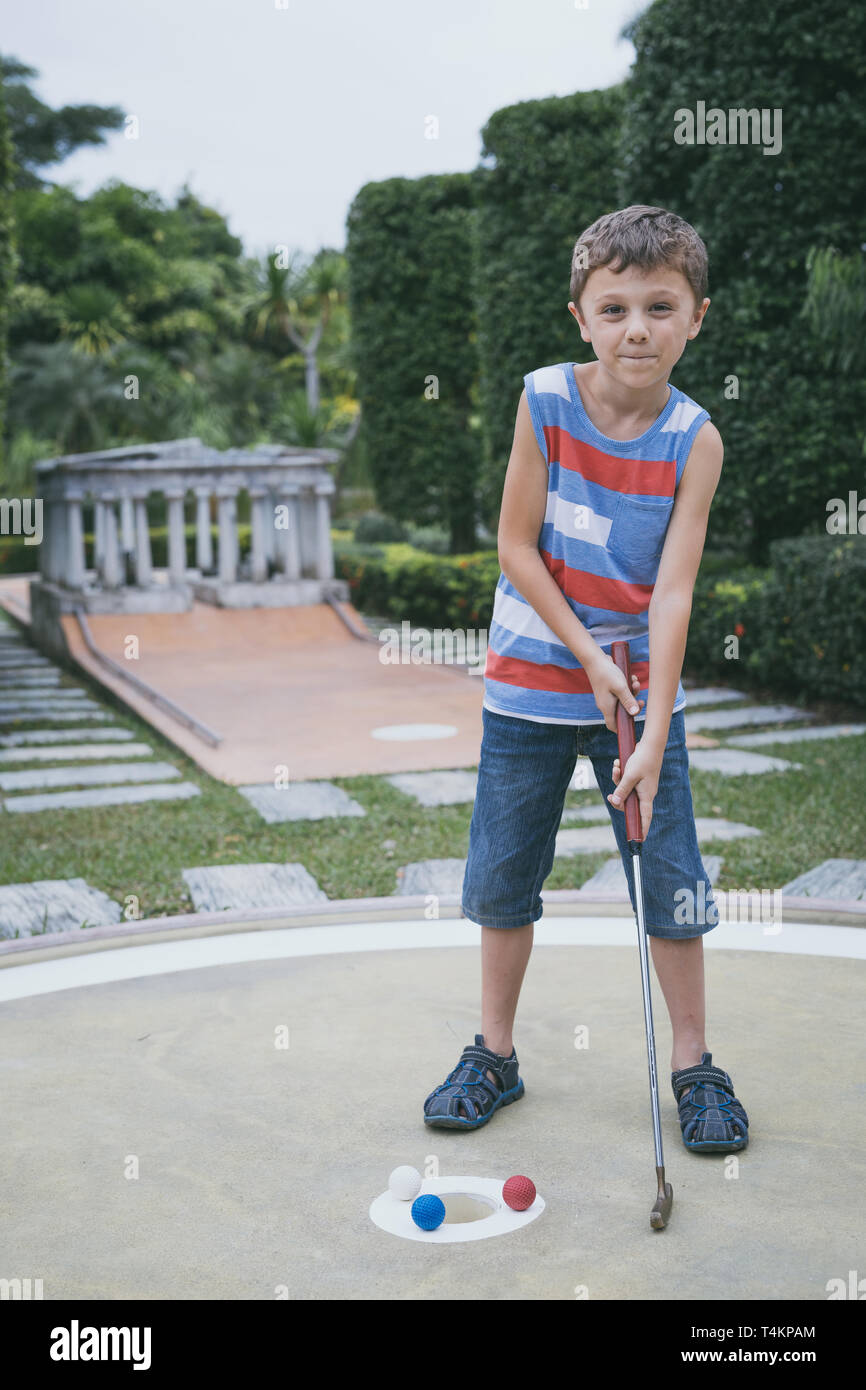 Happy little boy playing mini golf playing mini golf in a park at the ...