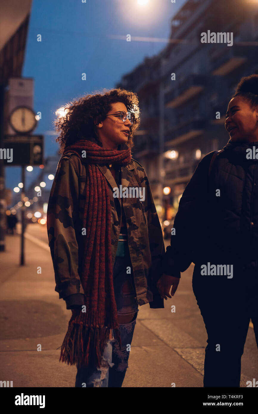 two young girl speaking in the street having funny conversation ...