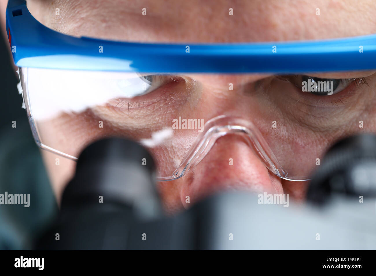 Male laboratory worker eyes looking at microscope wearing goggles Stock ...