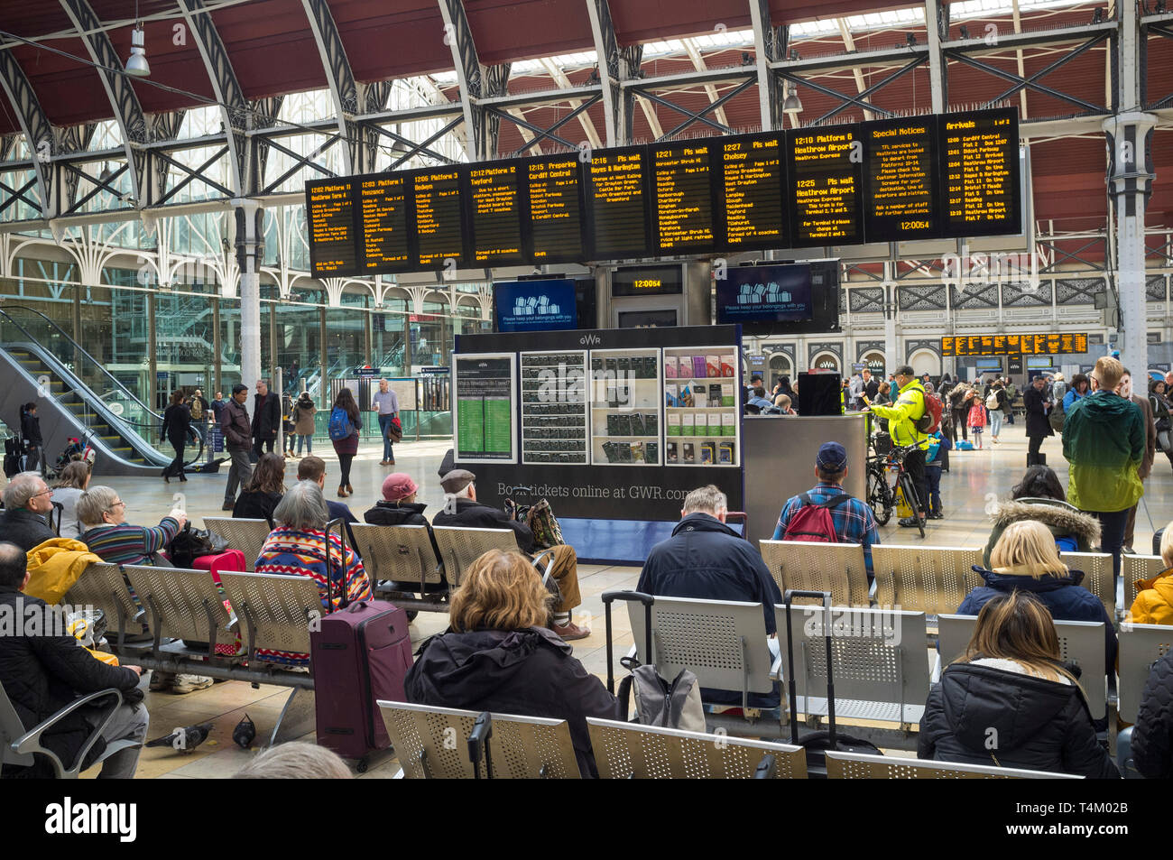 Travellers waiting by the illuminated display board at Paddington ...