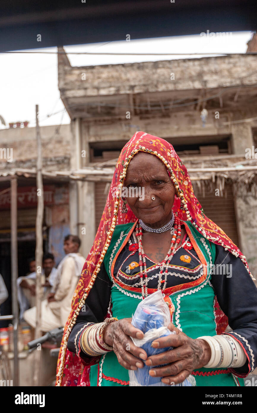 Old rajasthani woman dressed in local costume looking at tourists hi ...