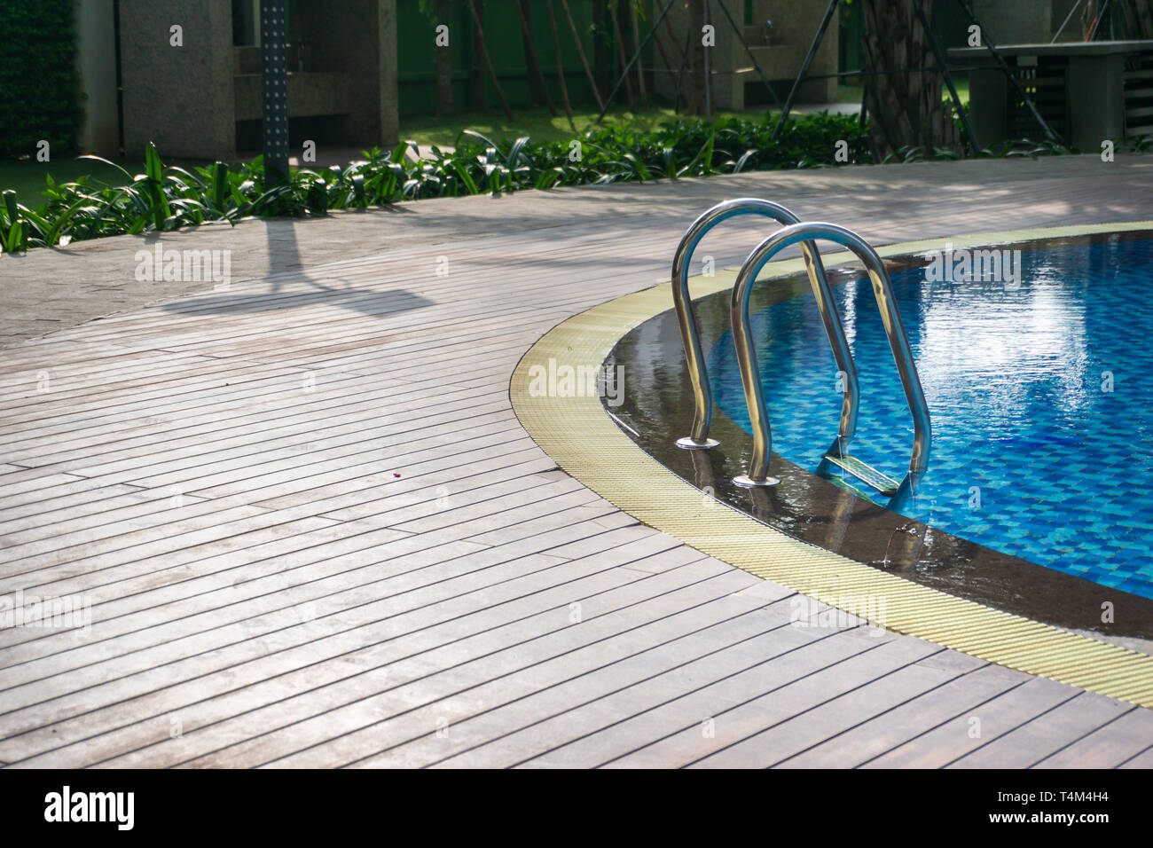 Blue swimming pool with wood flooring stripes Stock Photo - Alamy