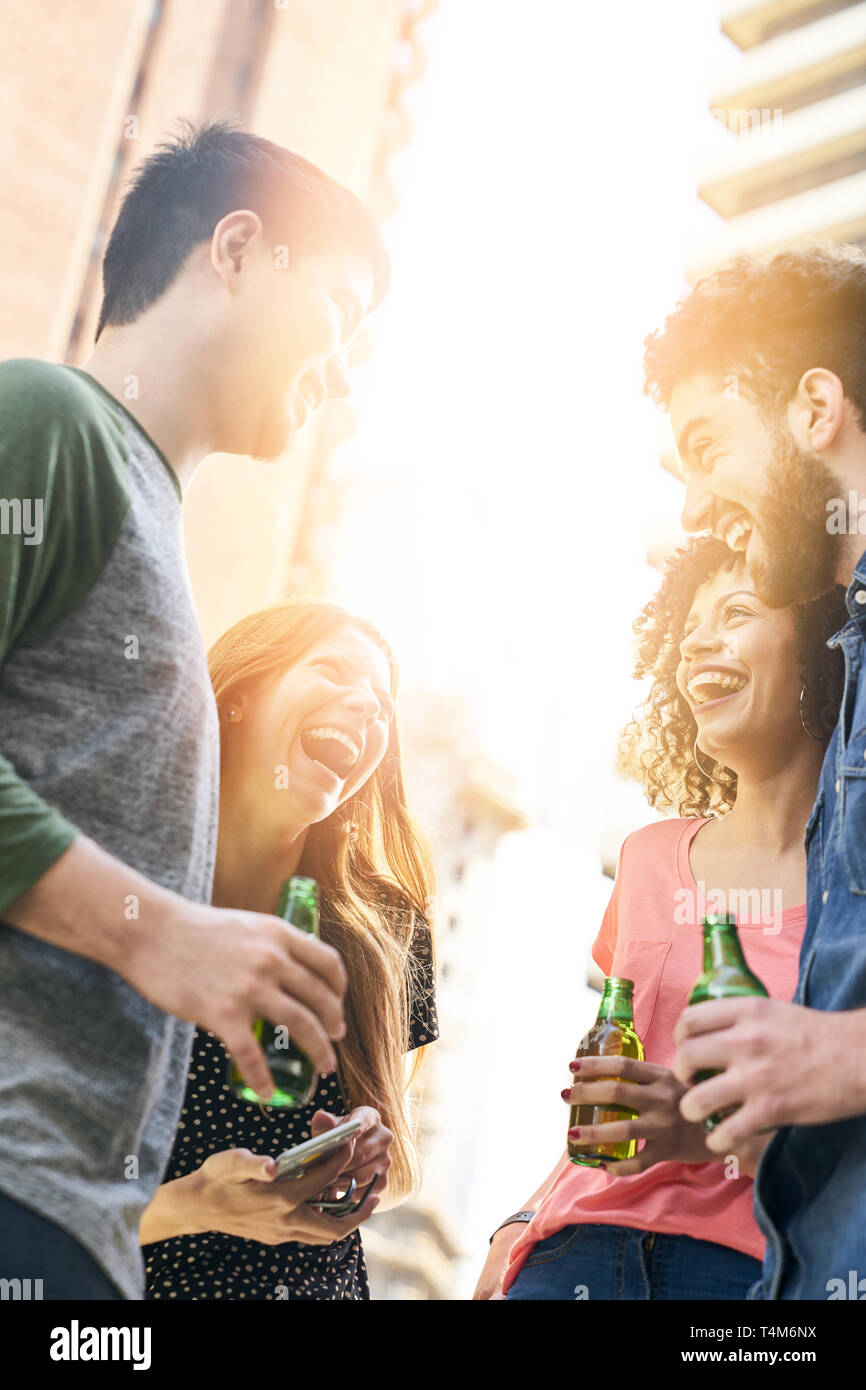 Laughing friends have fun at party with a bottle of alcohol in hand ...