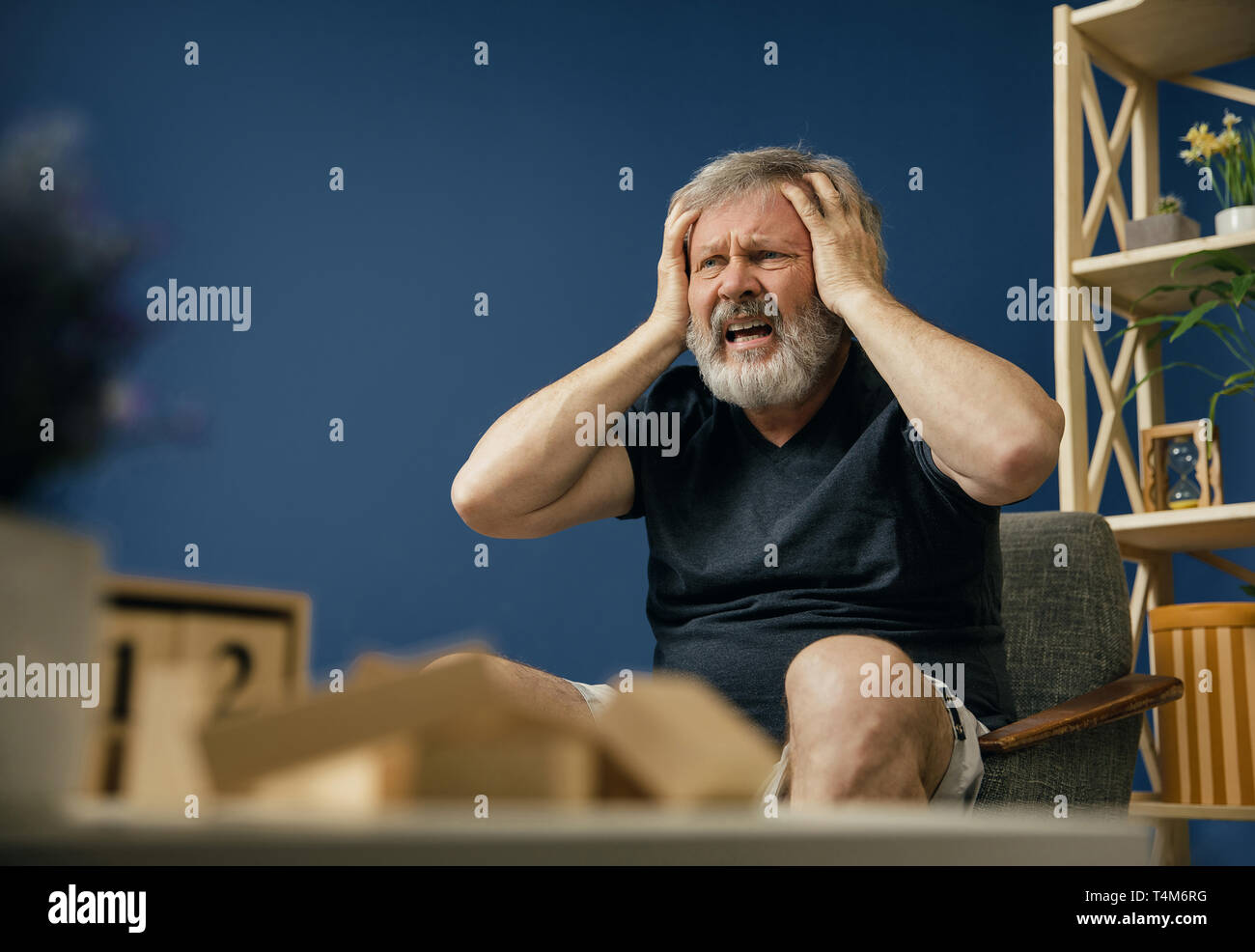 Screaming of pain. Old bearded man with alzheimer desease sitting on ...