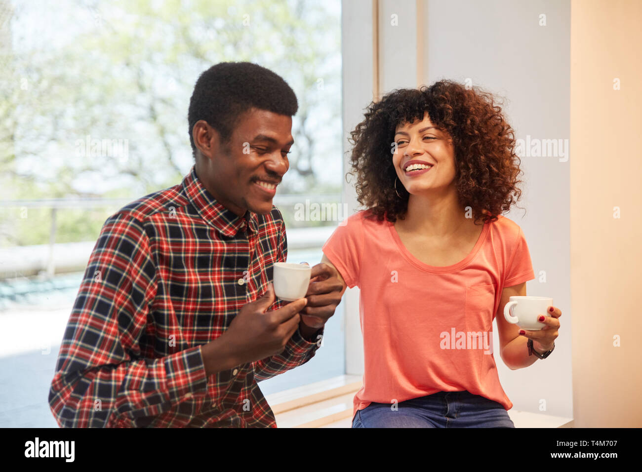 Two colleagues in the multicultural team have fun in a coffee break and ...