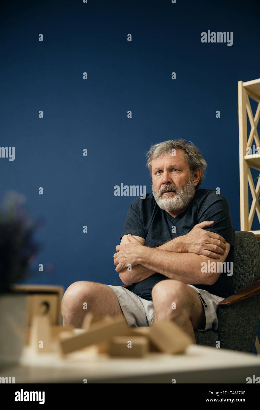 Lonely. Old bearded man with alzheimer desease sitting on the chair and ...
