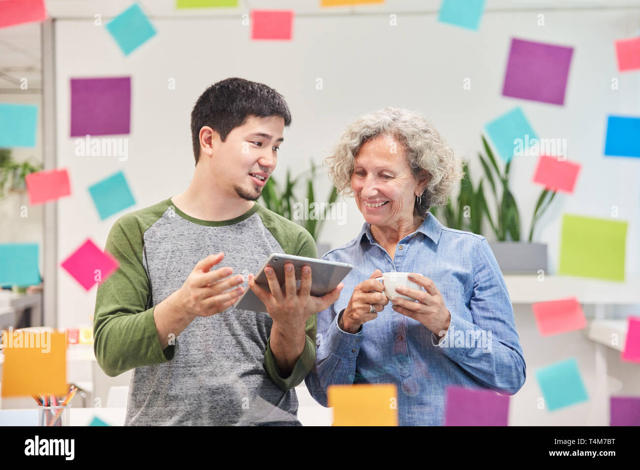 Young software developer explains senior woman a computer app ...