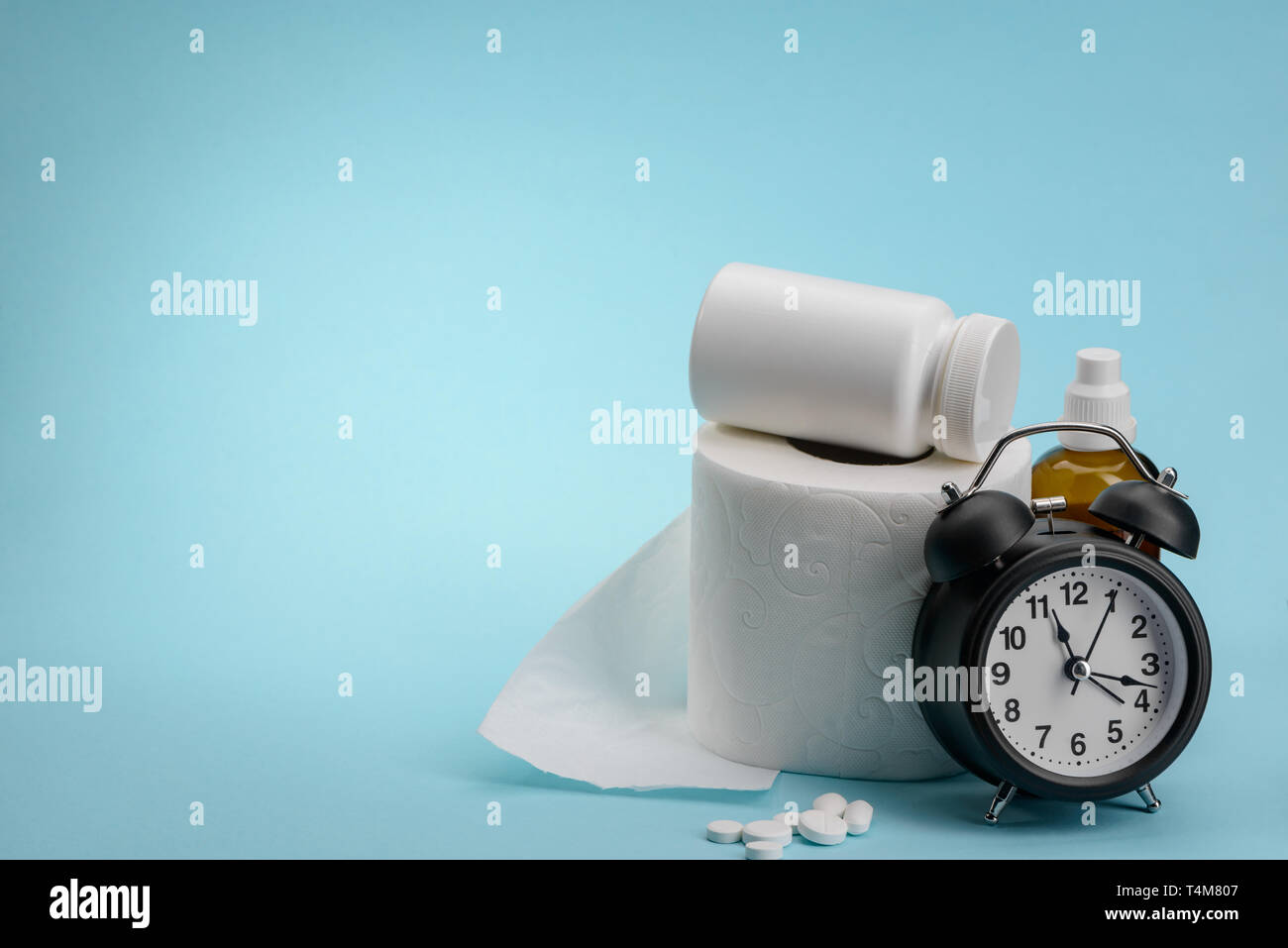 Medicine, toilet paper and alarm clock on blue background with copy ...