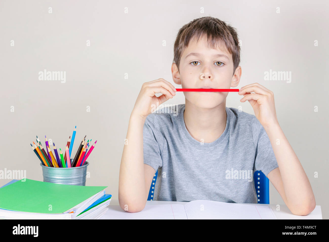 Kid doing homework at the table and thinking or dreaming Stock Photo ...
