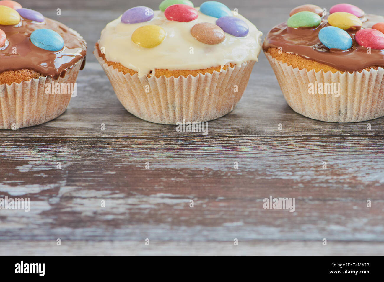 muffins coated with chocolate in a row, wooden background with copy ...