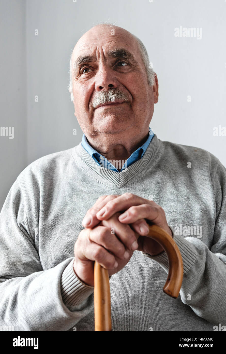 Nostalgic elderly man with a walking cane or stick sitting thinking on ...