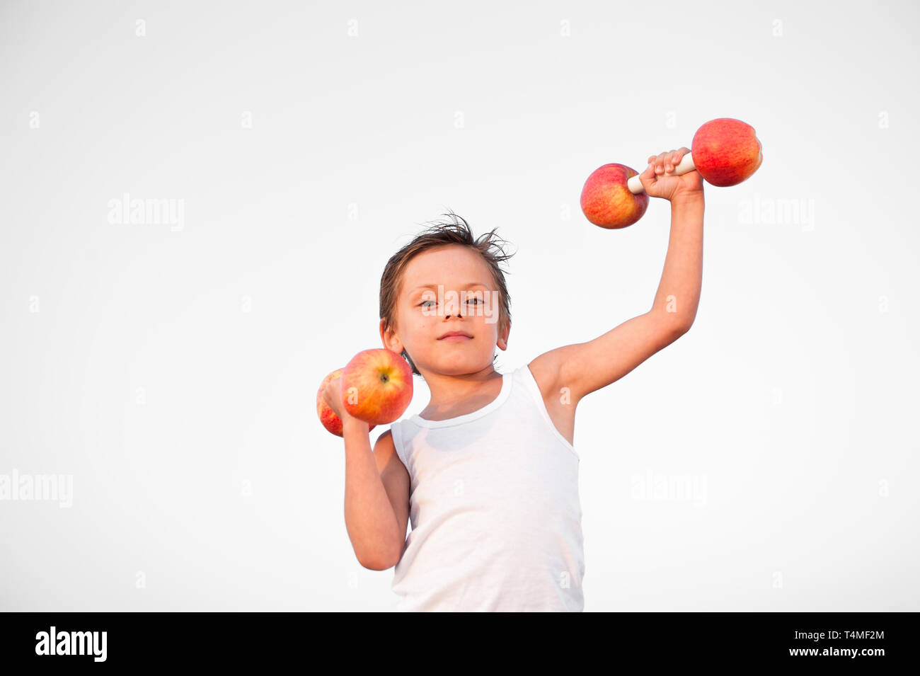 one little caucasian boy in white tank top lifting apple fruit ...