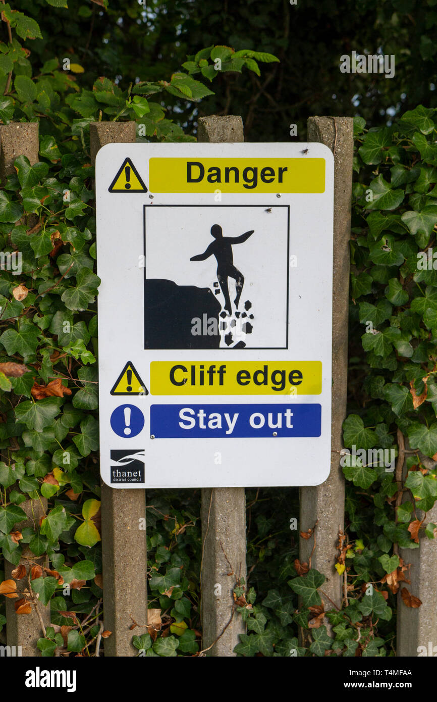 A sign warning walkers of a nearby cliff edge on the coastal path ...