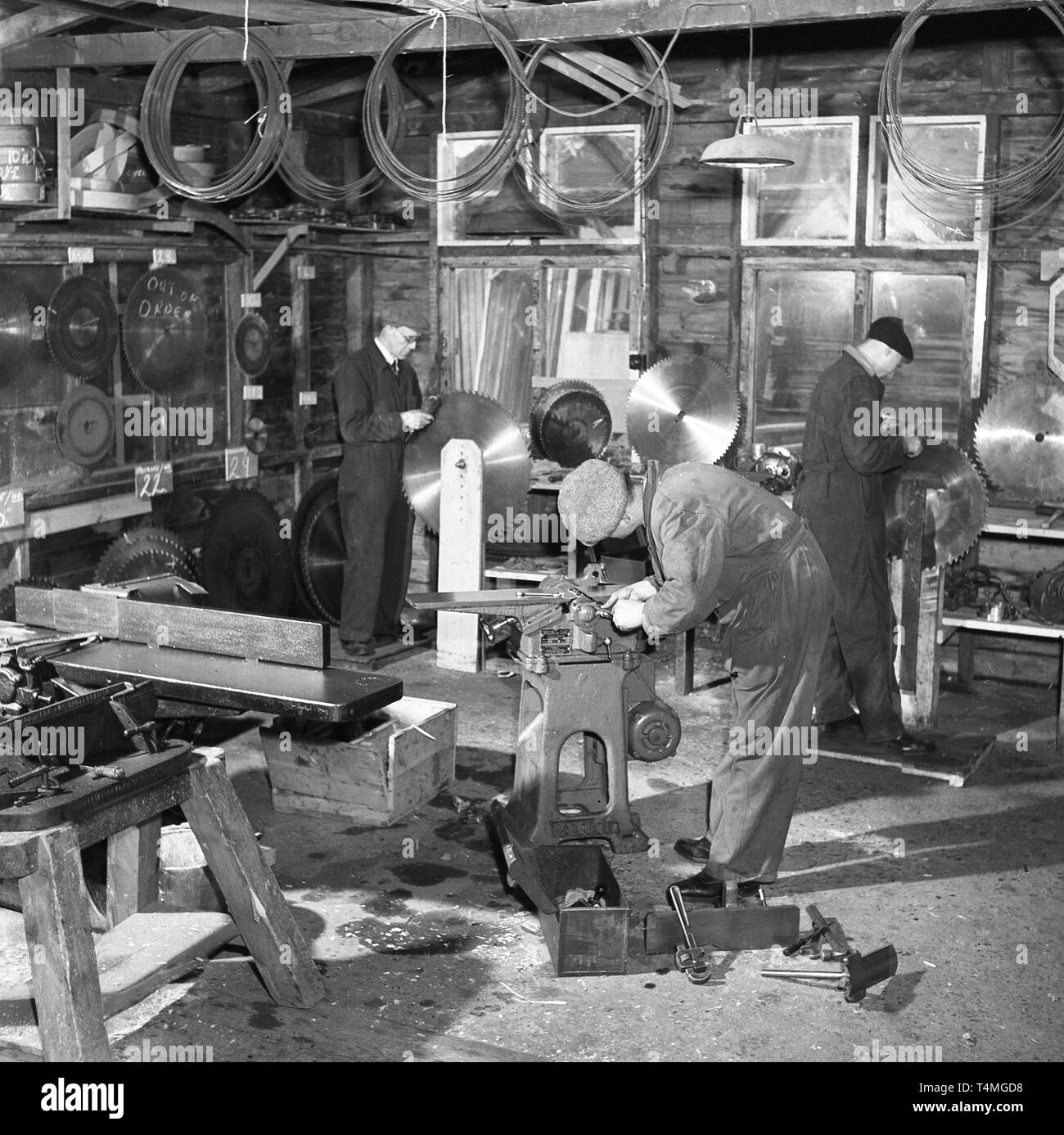 1950s, historical, workers in workshop using metal saw grinders or ...