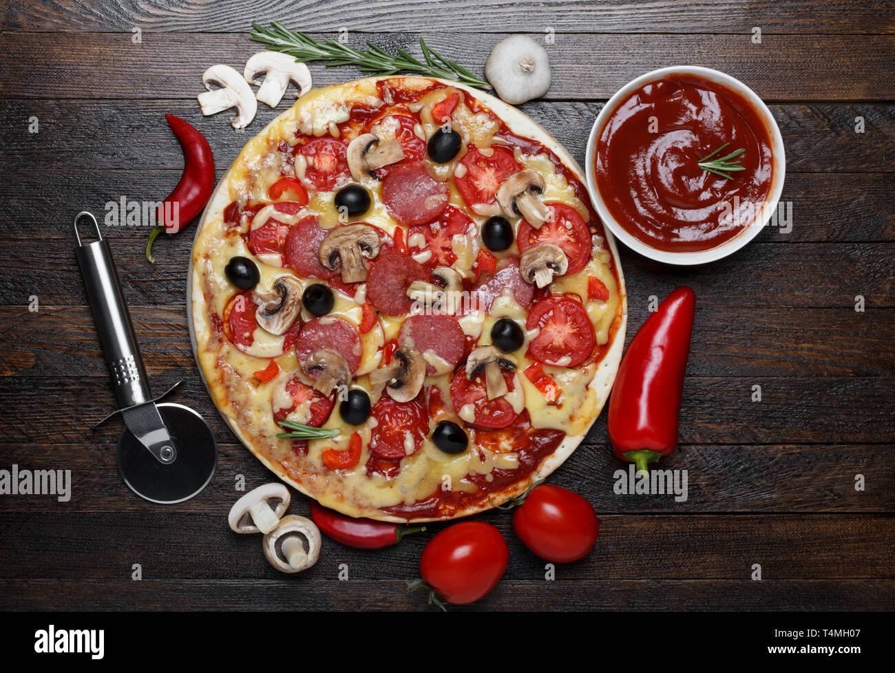 Hot pizza on rustic wooden table with ingredients and cutter Stock ...