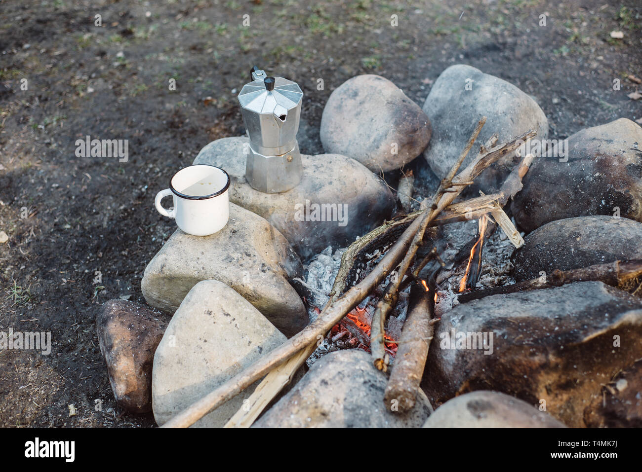 Horizontal outdoor image of white cup and coffee maker near to bonfire ...