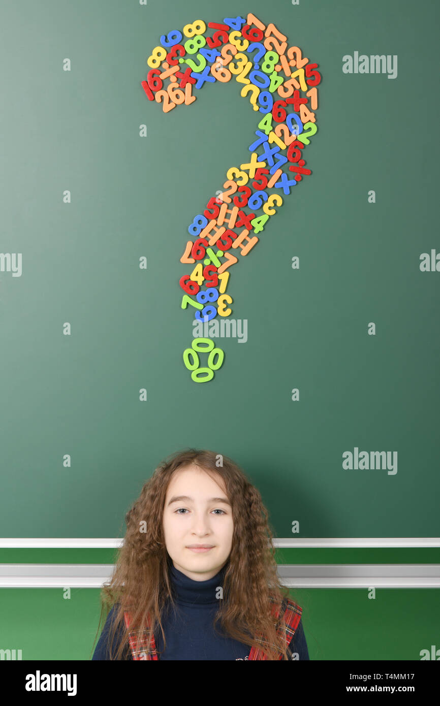 Smiling little schoolgirl on green school board. A magnetic question ...