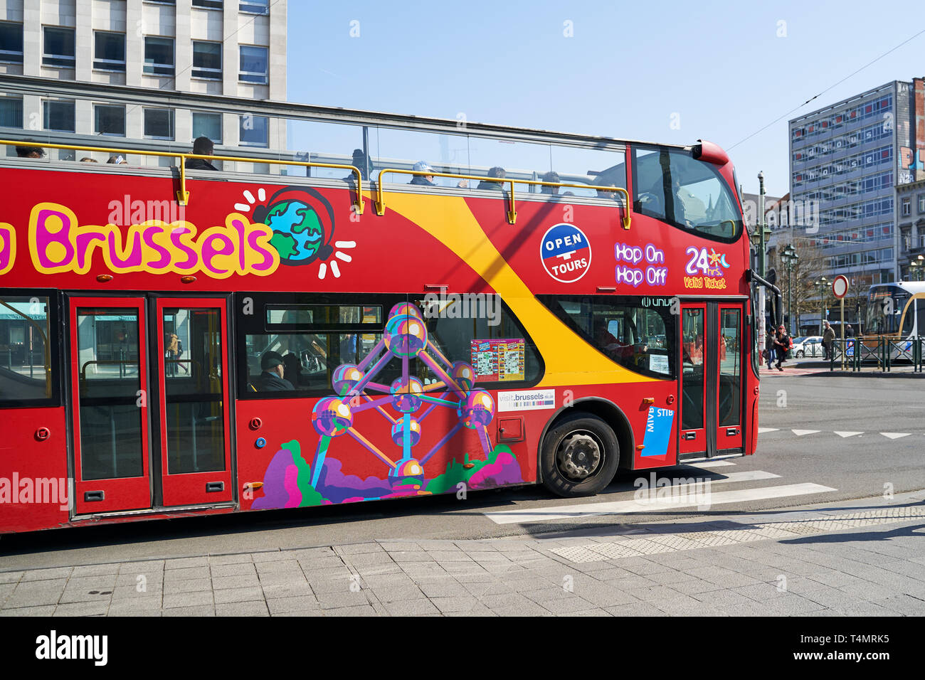 Red tourist sightseeing bus with people on one of the central streets ...