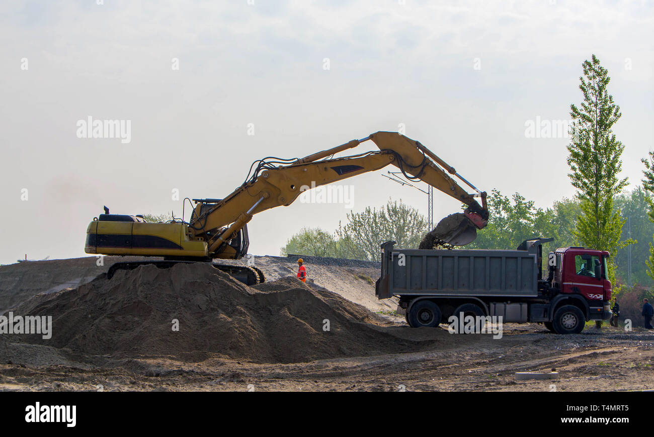 Excavator loading sand in the truck on the construction of access roads ...