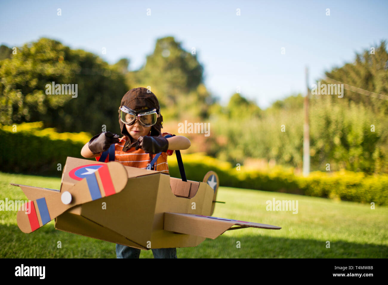 Young boy having fun pretending to be a pilot in a cardboard plane ...