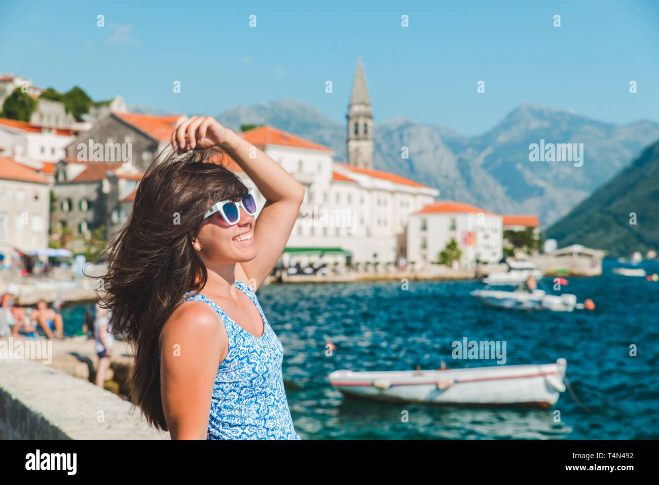 woman walking by Perast city. summer vacation. sea bay. mountains on ...