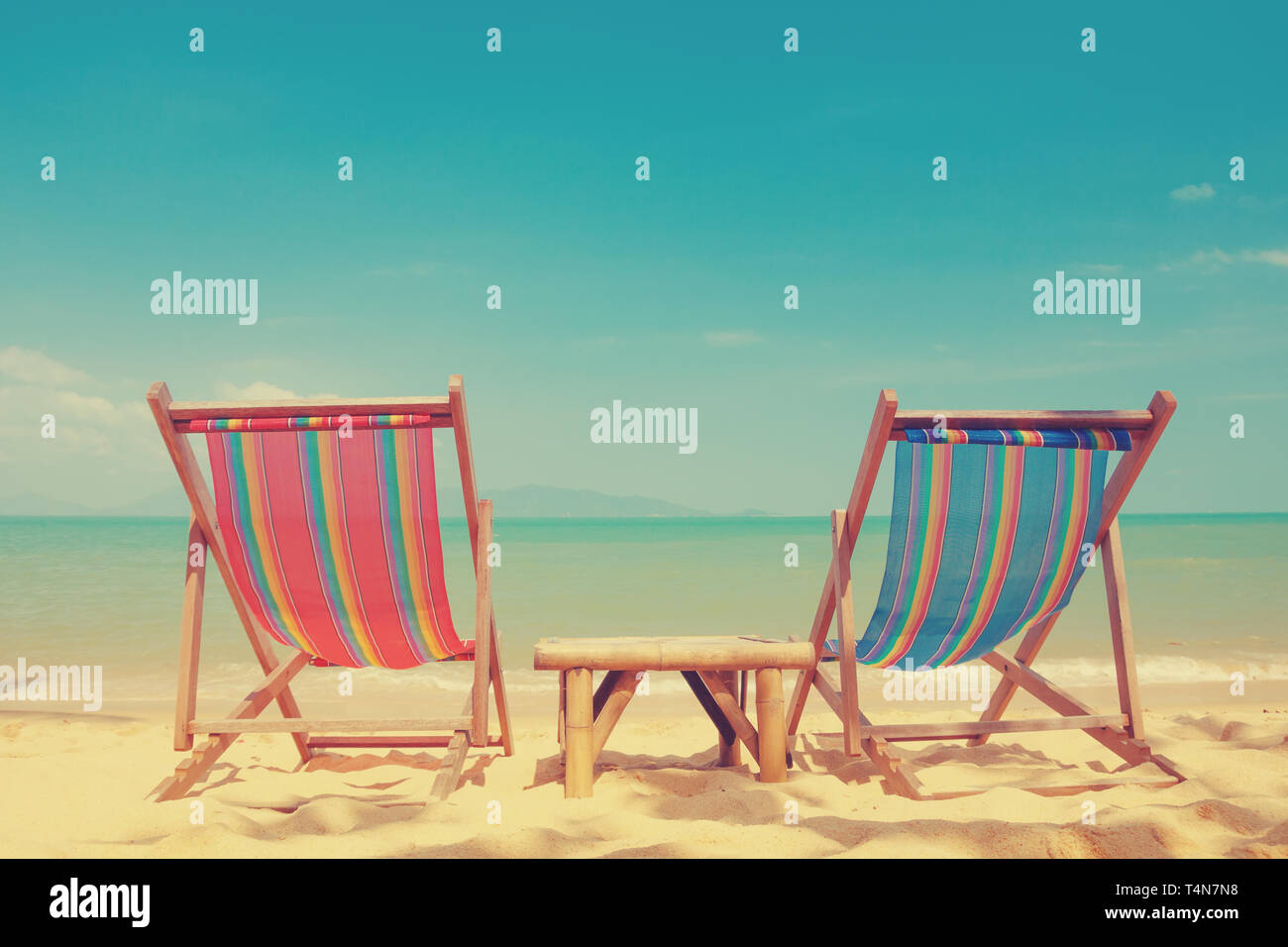 Vintage toned two beach chairs on tropical shore Stock Photo - Alamy
