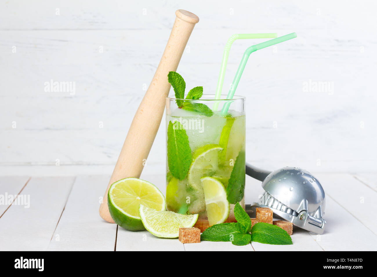 Mojito cocktail on wooden table with lime, mint, sugar, muddler and ice ...