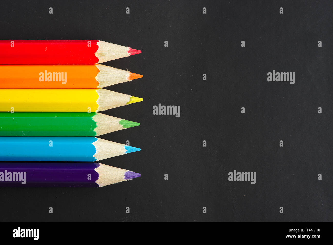 six rainbow colored pencils on a black sheet with space for text Stock Photo - Alamy