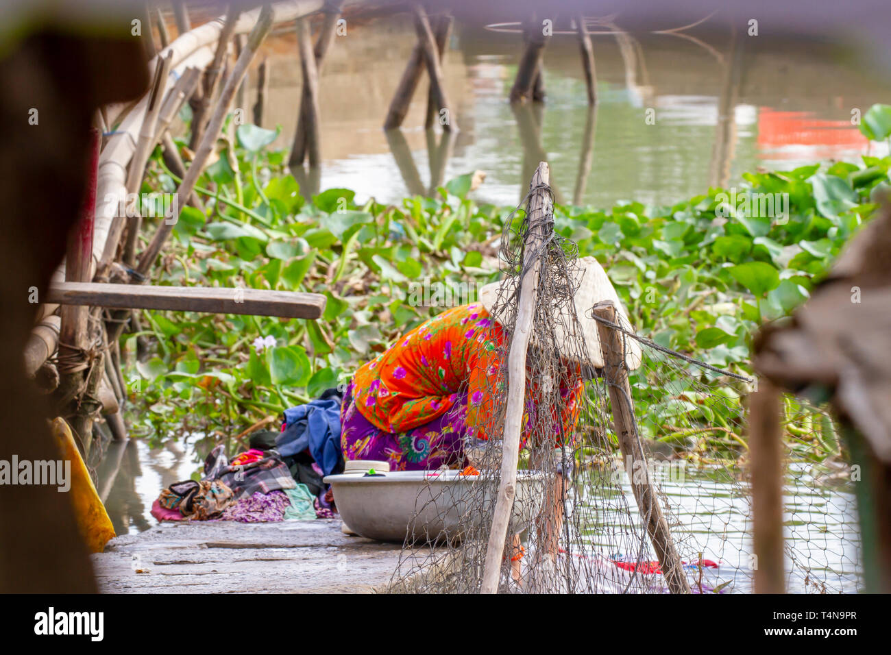 Woman in colorful traditional attire washing laundry of dock in Mekong ...
