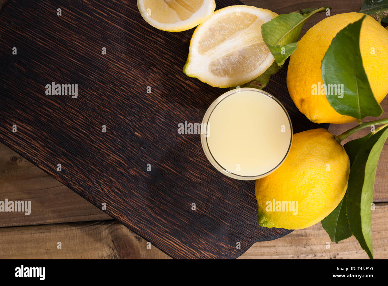 limoncello in a glass and fresh citrus fruits with green leaves ...