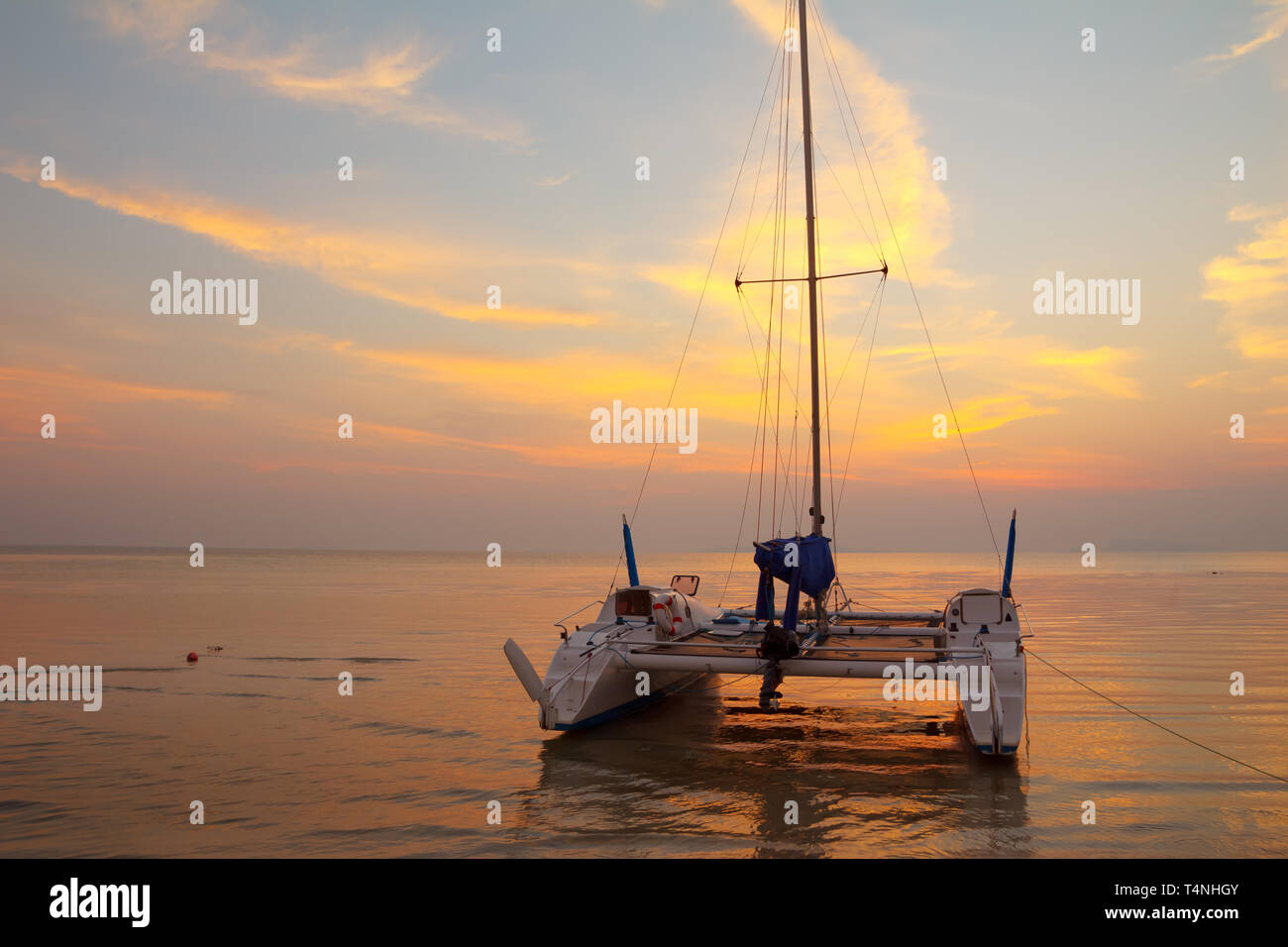 Catamaran on tropical beach at sunset Stock Photo - Alamy