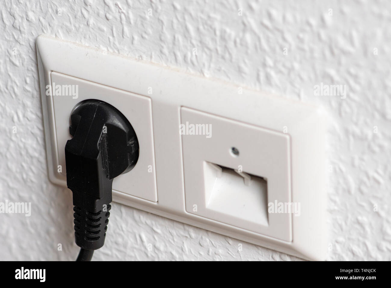 Socket with plug on a wall with data cable socket Stock Photo - Alamy