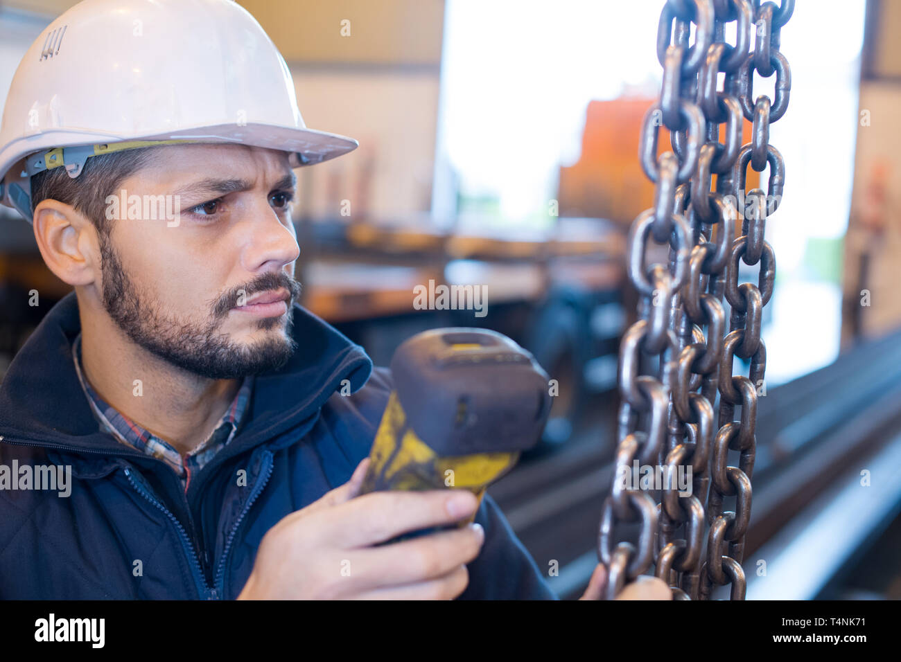 man in industrial building holding chains Stock Photo - Alamy