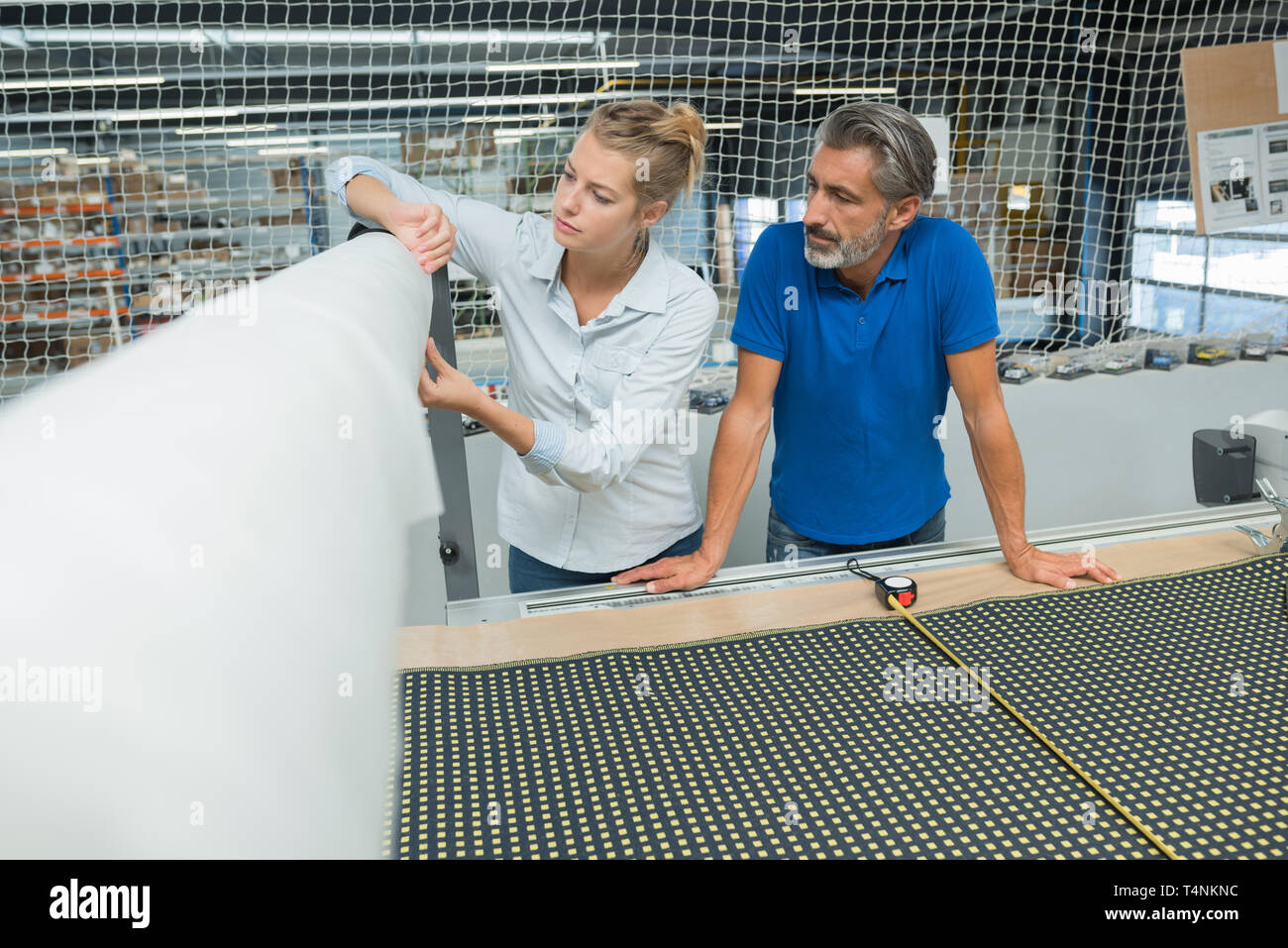 workers unrolling material on to work bench Stock Photo - Alamy