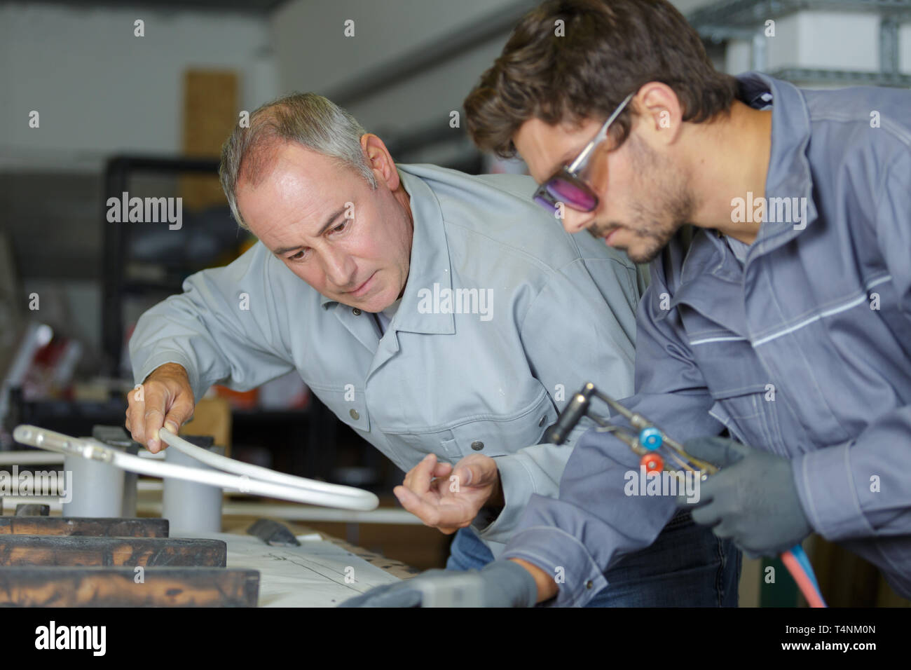man overseeing trainee working with blowtorch Stock Photo - Alamy