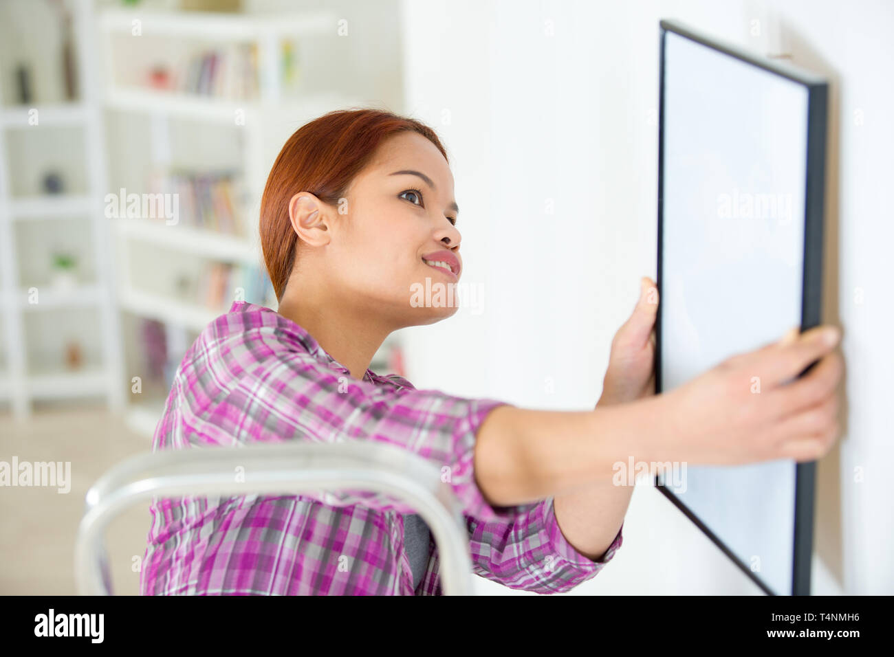 woman hanging picture frame on the wall Stock Photo - Alamy