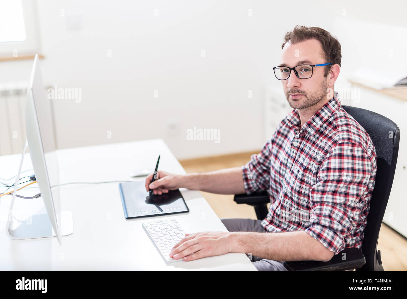 Portrait of graphic designer sitting at the desk and using his desktop ...