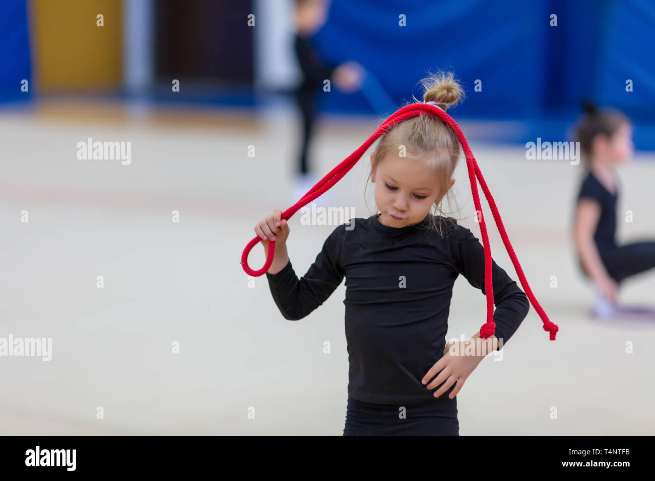 little gymnast is holding the rope over her head while exercising Stock ...
