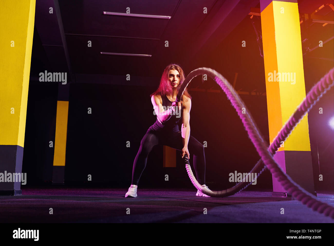 Fitness woman using training ropes for exercise at gym. Athlete working ...
