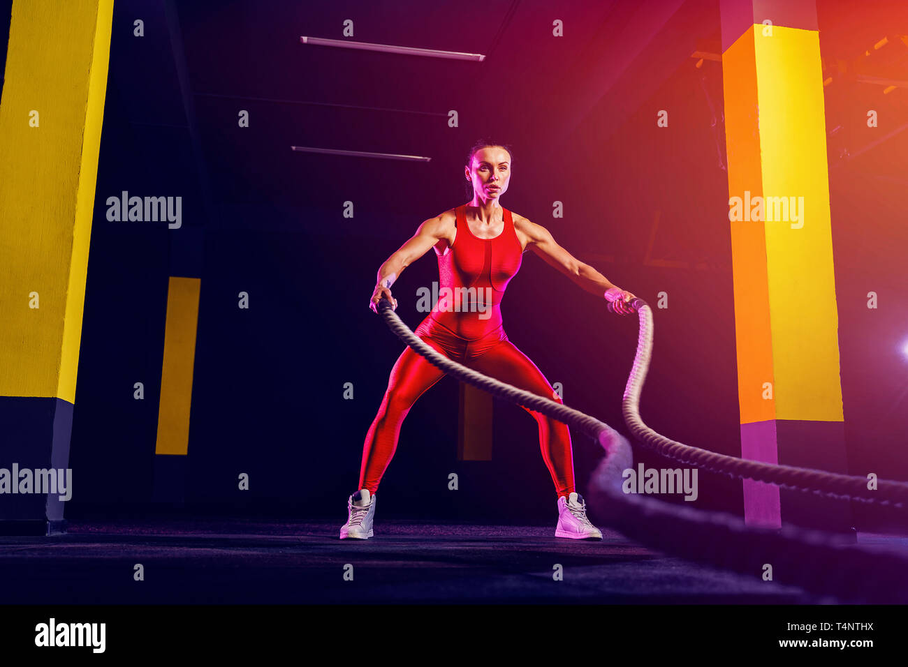 Fitness woman using training ropes for exercise at gym. Athlete working ...
