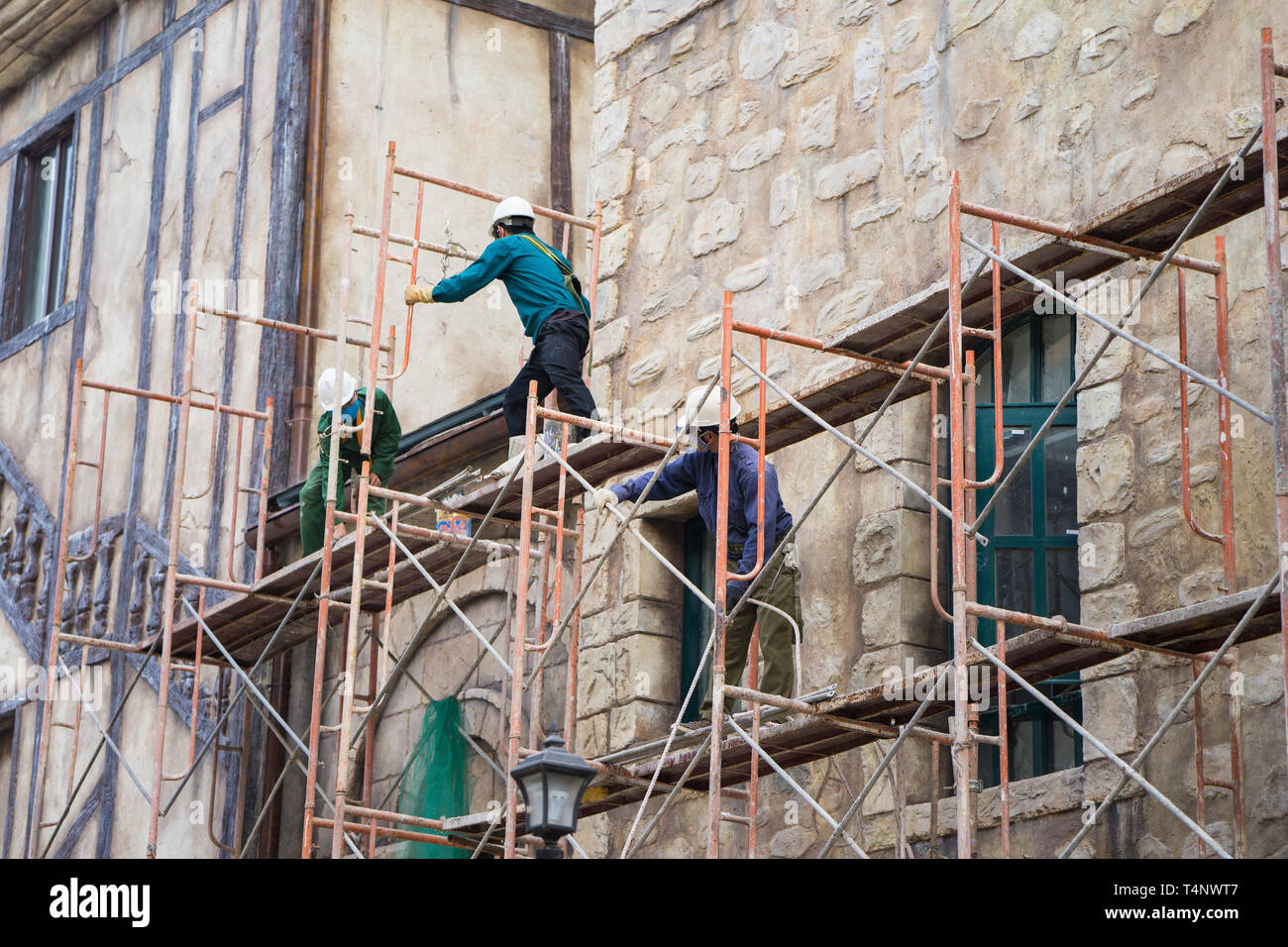 Workers with no protection belt fixed on scaffold at construction site ...