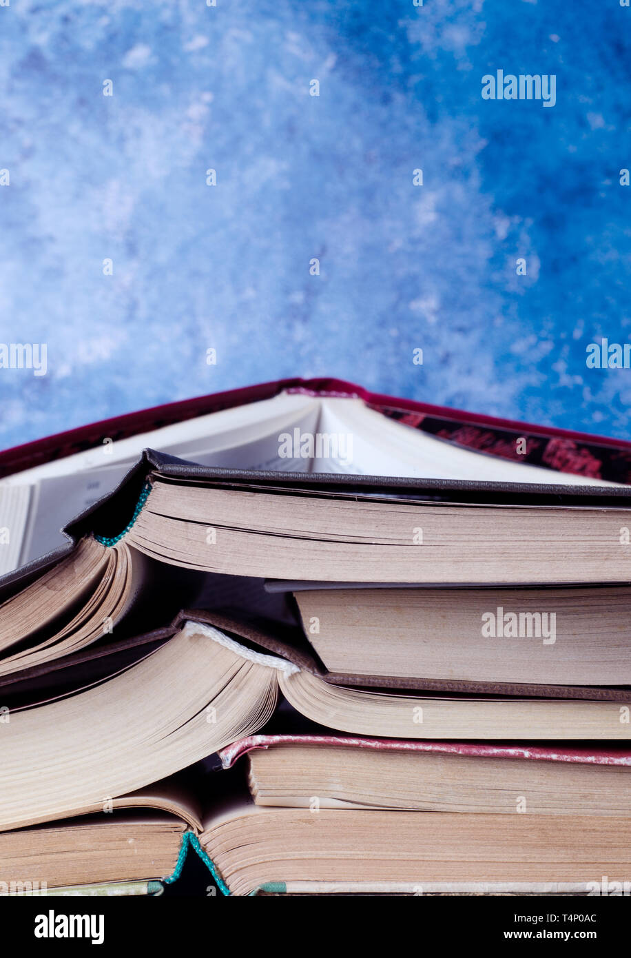 Stack of books piled against blue background. School concept Stock ...